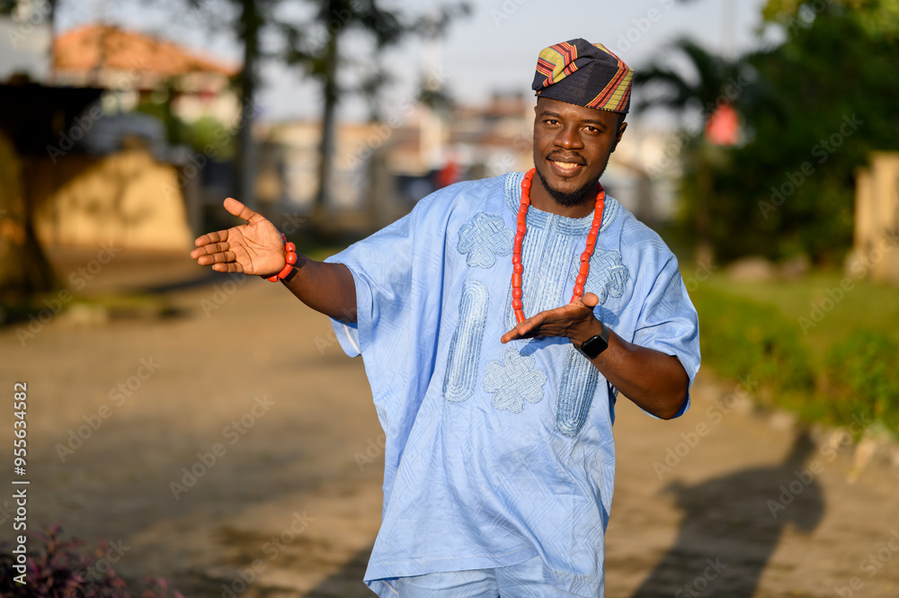 Young handsome Yoruba man in traditional attire pointing right to ...