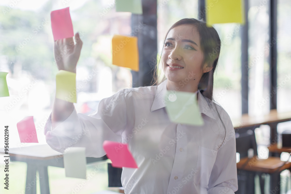Young Serious asian Creative team use post it notes to share idea ...