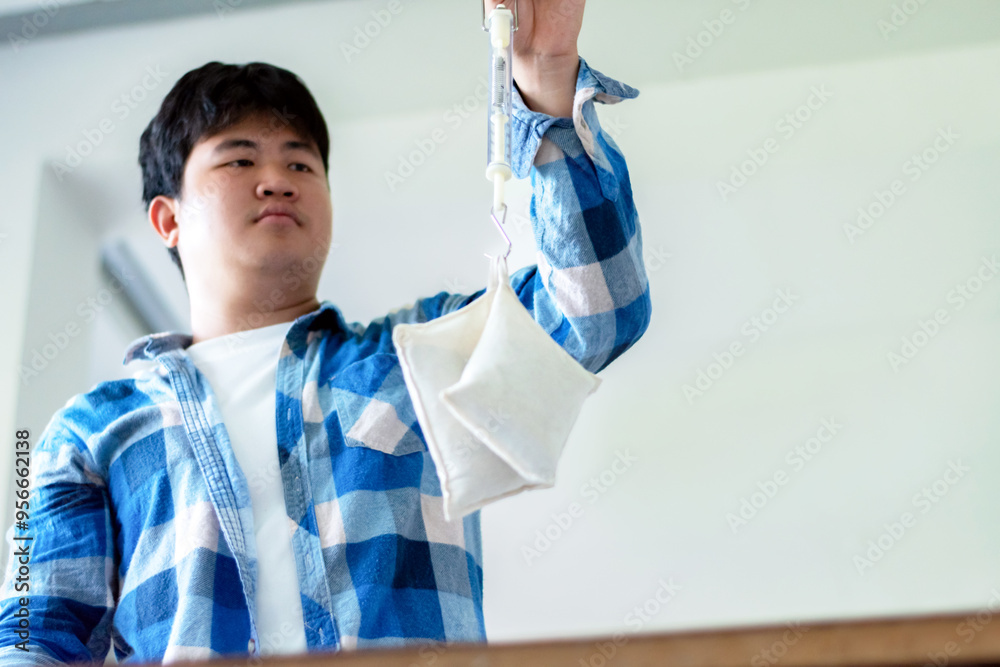Asian student doing a physics experiment on the weight of objects using ...