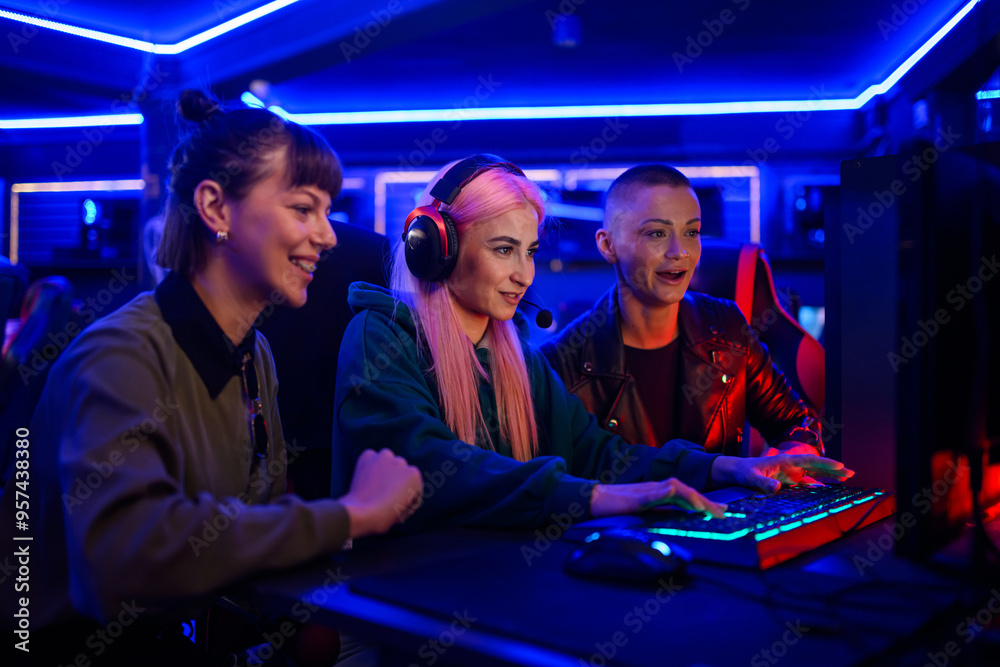 Gamer girl with headset playing a video game while her friends cheering ...
