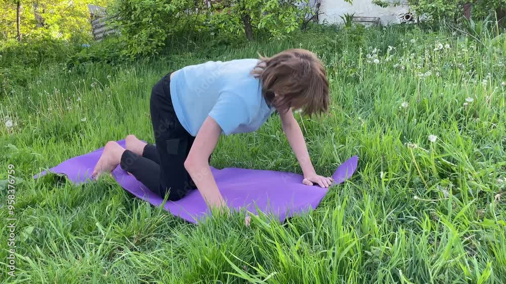 Young man practicing the cat cow yoga pose on a mat in a grassy ...