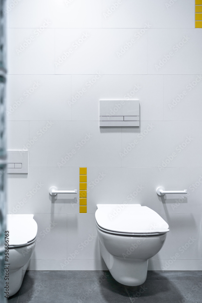 Flush buttons on a minimalist white-tiled wall in a public restroom ...