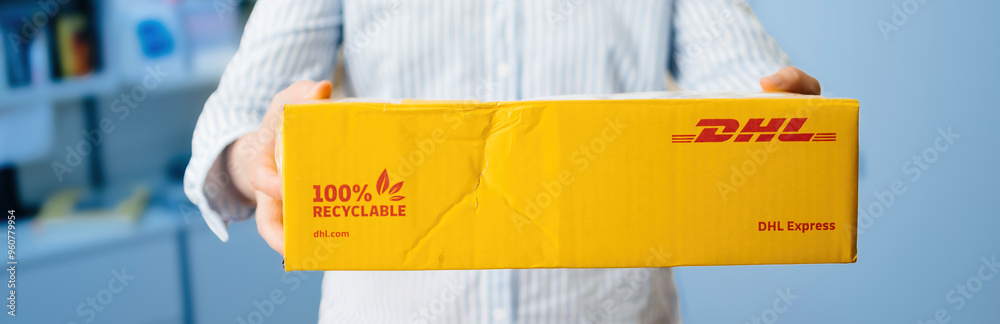 Frankfurt, Germany - Jun 11, 2024: A courier woman holding a DHL ...