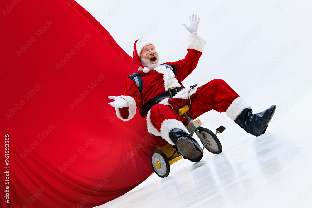 Santa Claus on small tricycle, holding red bag of gifts behind him ...
