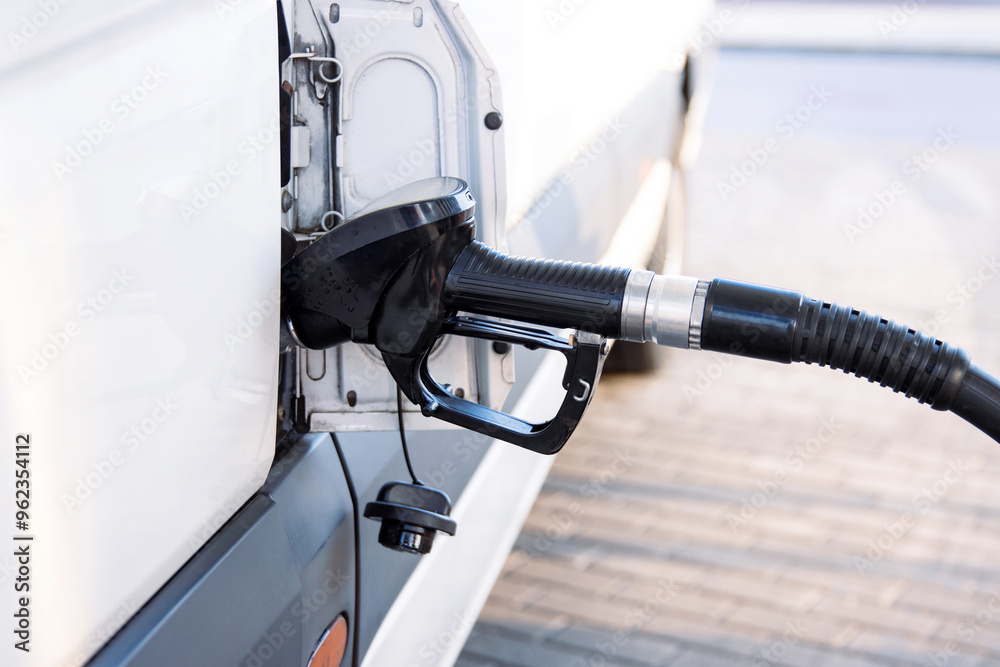 Closeup of a fuel nozzle in the car tank. Process of refilling a white ...