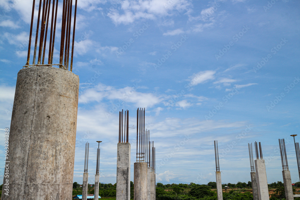 Construction site with concrete pillars and steel bars against a blue ...
