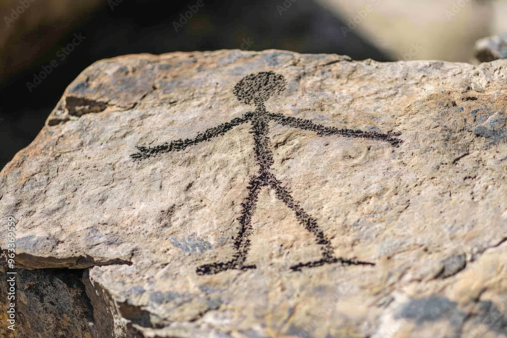 A stick figure drawing on a rock, representing ancient rock art or ...