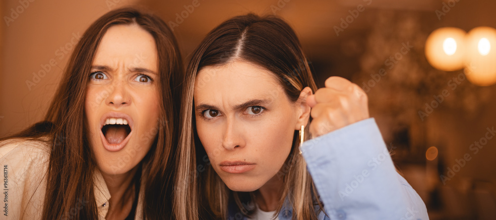 Portrait of a two crazy angry mad women screaming to camera, sitting in ...