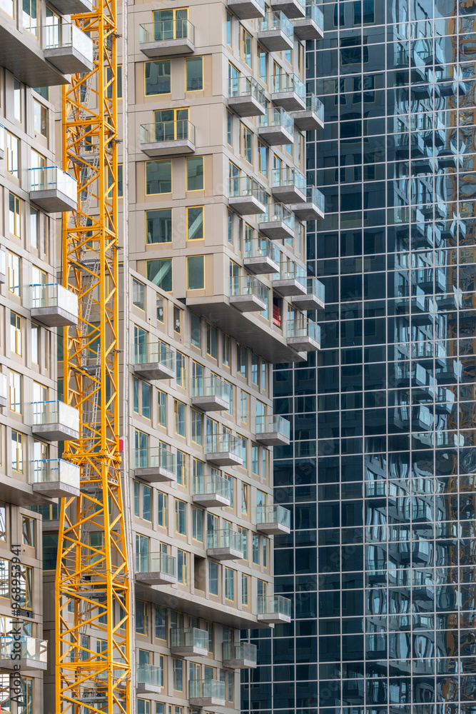 A high-rise building with balconies stands tall next to a bright yellow ...