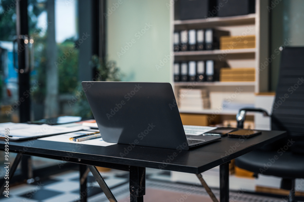 An empty office desk at night with a laptop displaying a business chart ...