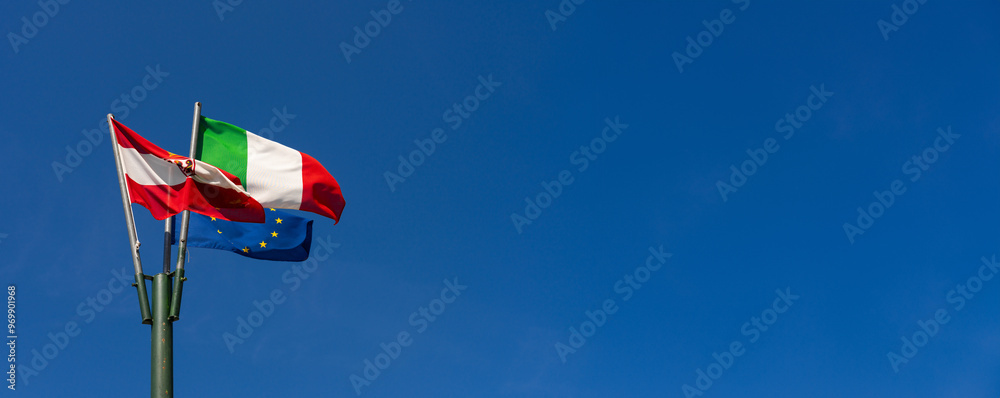 Italian, Austrian, and European Union flags flutter together on a ...