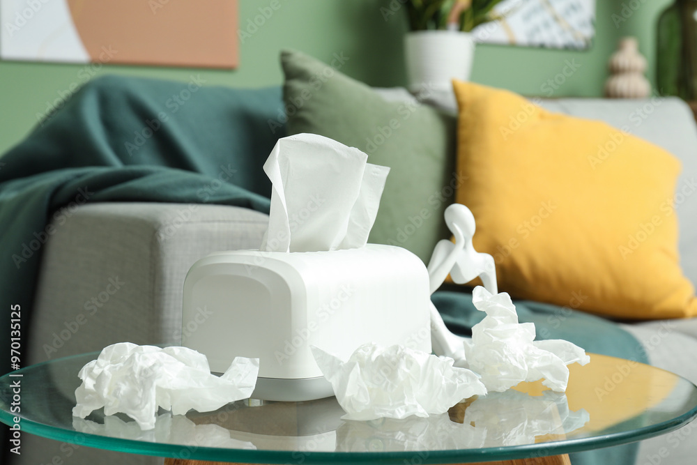 White paper tissue box and crumpled tissues on glass coffee table in ...