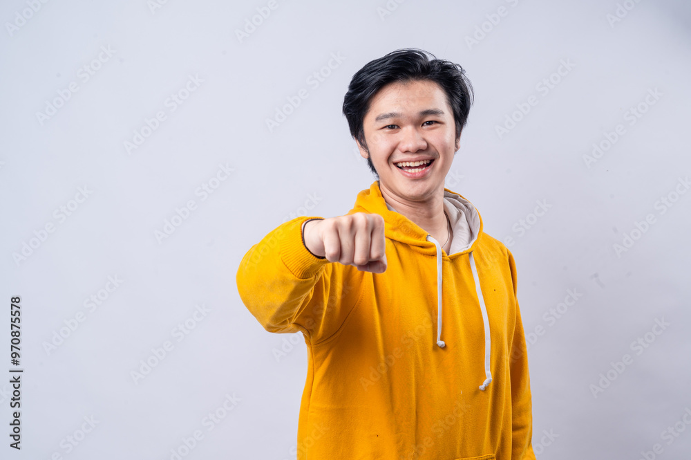 An Asian man in a yellow hoodie strikes a playful punch pose, looking ...