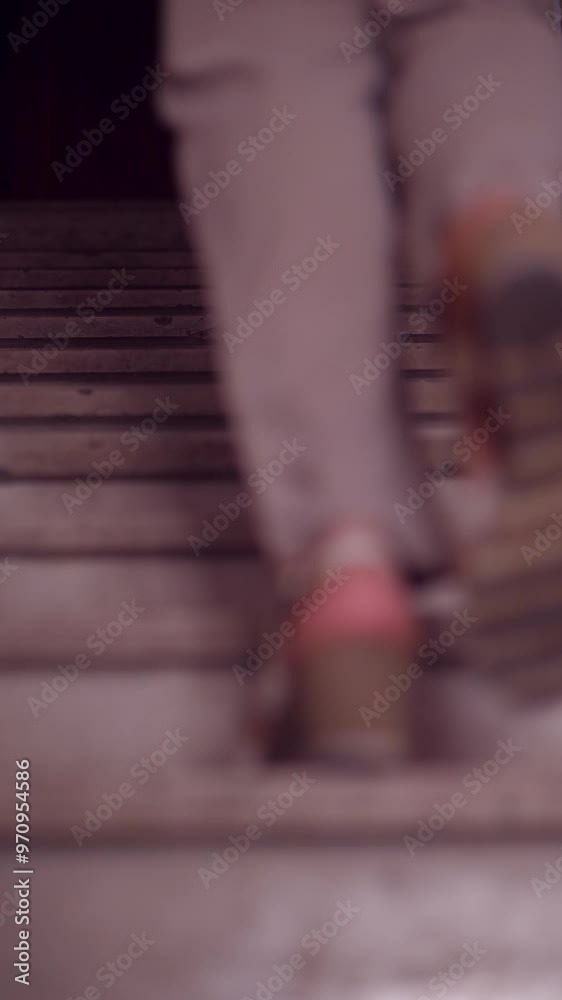Vertical video of a close-up of woman's legs walking up stairs, showing ...