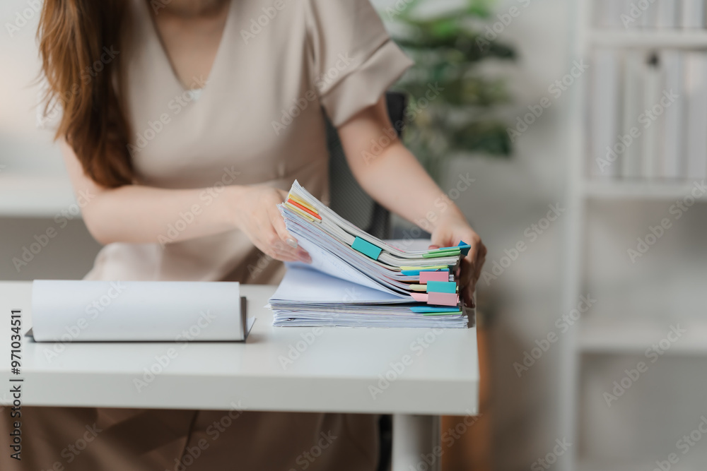 Organized Efficiency: Woman meticulously sorts and arranges a stack of documents, color-coded ...