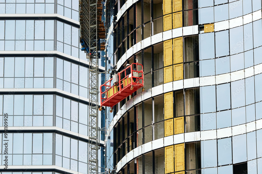 Suspended platform at height during glass facade panel installation on ...