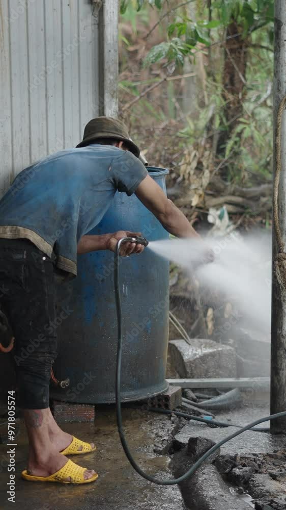Young mechanic washing his hands and arms after a day's work in a small ...