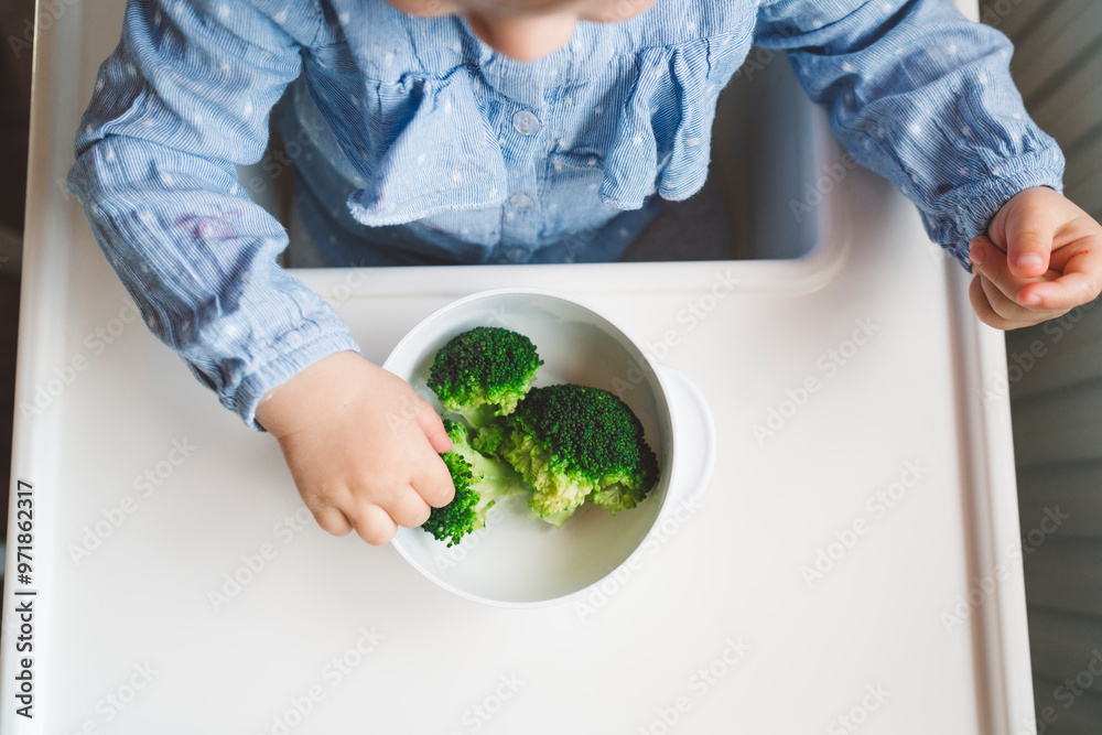 The baby is trying a new taste of solid food. Eating healthy food from ...