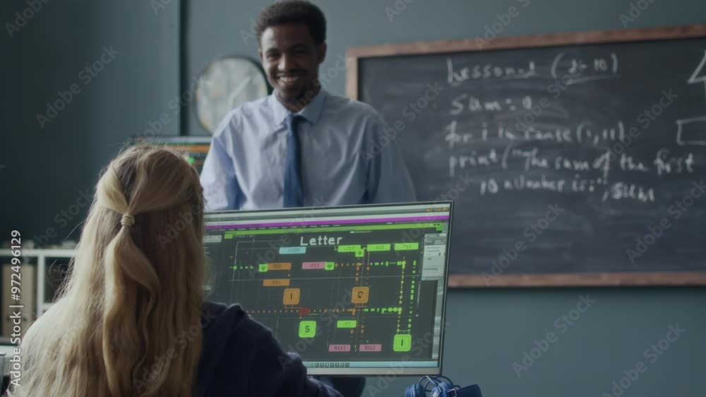 Medium shot of Black male programming teacher speaking to Caucasian ...