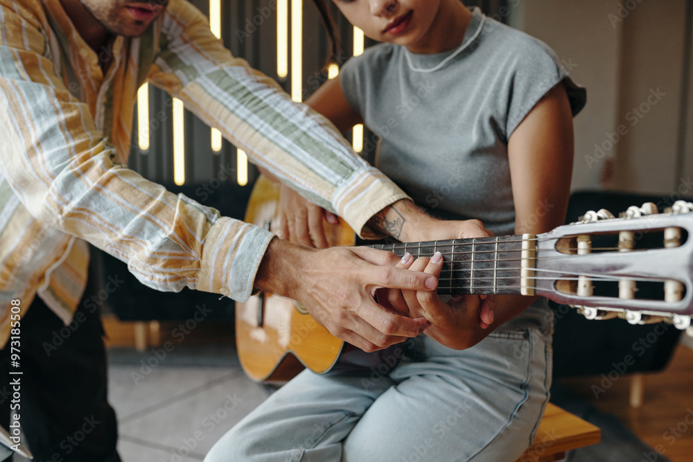 Man providing guitar lesson to young woman sitting on chair in cozy ...