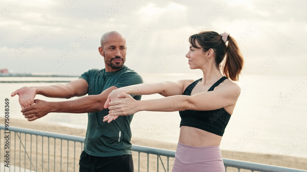 Male and female athletes in summer exercises their shoulders and arms ...