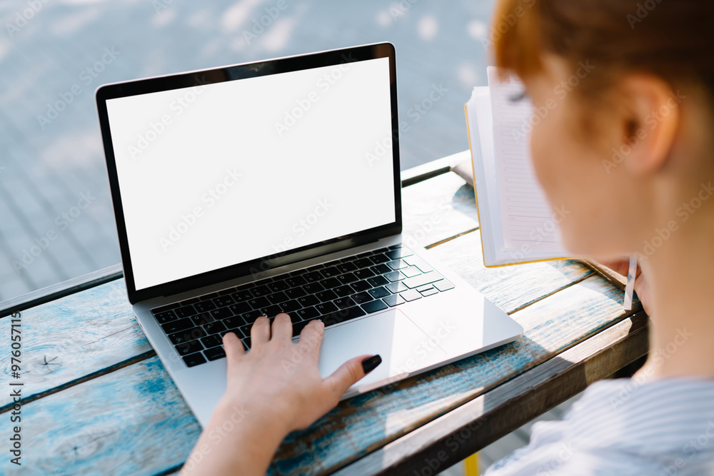 Back view of redhead young woman typing on laptop computer using ...