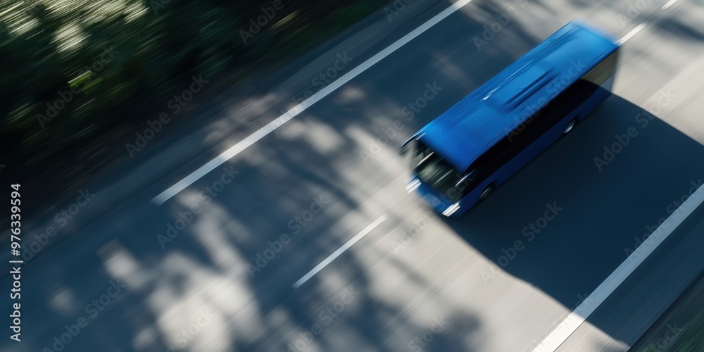 A blue bus moves rapidly along a tree-lined road, emphasizing speed ...