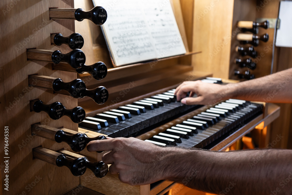 Left side view of Organist playing organ and changing Organ registers ...
