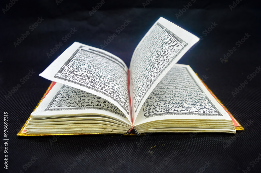 Open Quran book with intricate Arabic script on black background ...