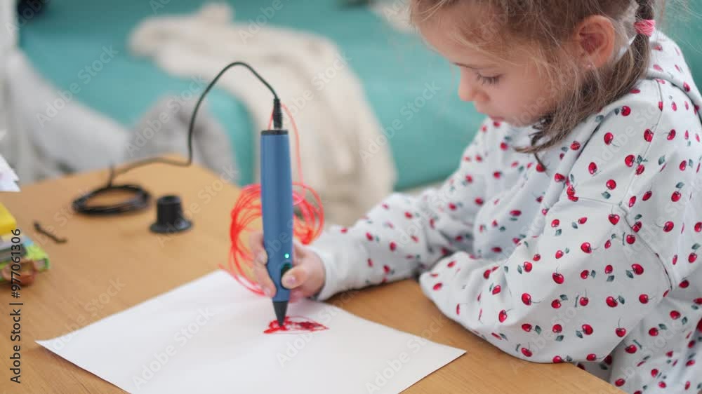 Little girl sits at her desk in her room using 3D pen to create plastic ...