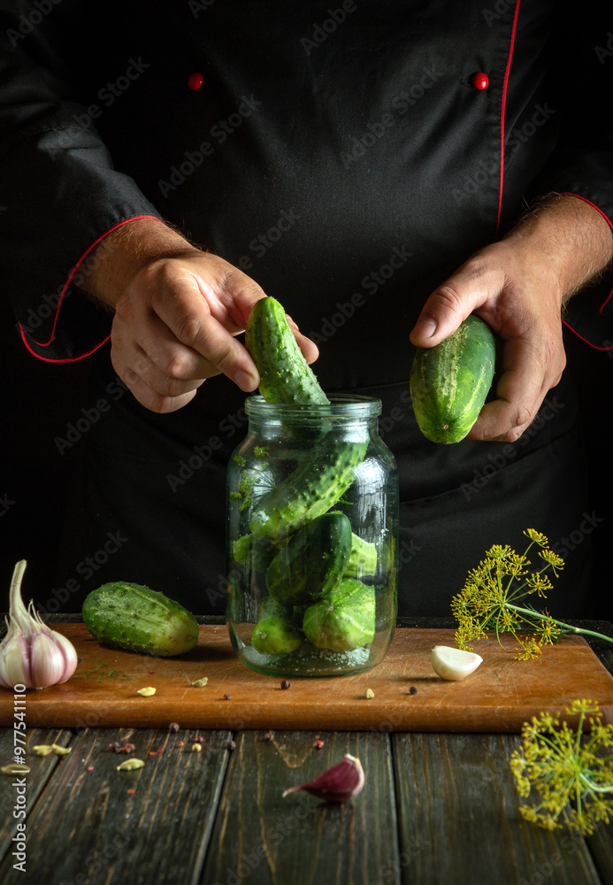 Cooking pickled cucumbers in a jar by the chef in a restaurant kitchen ...