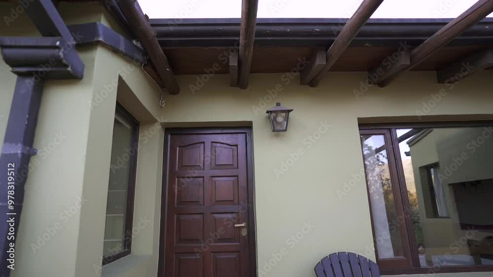 Modern house exterior featuring a wooden door, overhead beams, and ...