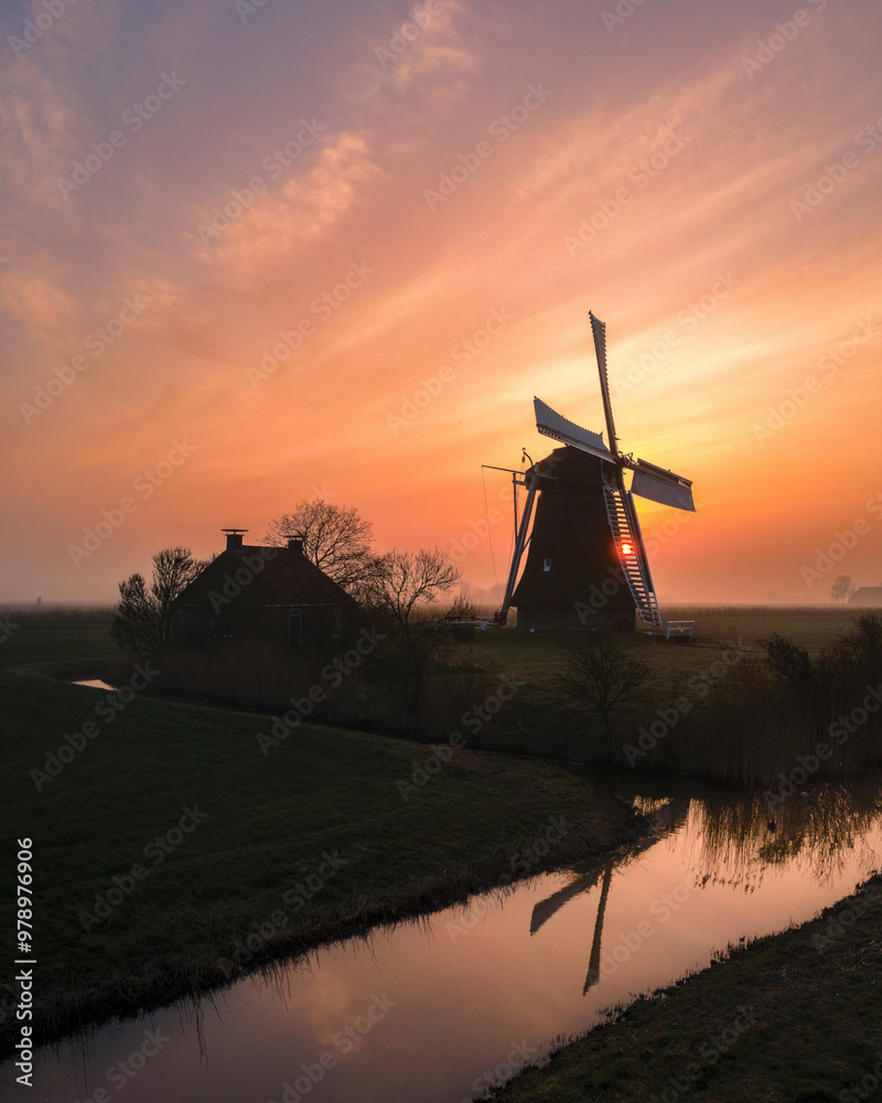 Aerial view of a serene sunrise over a traditional windmill and quaint ...