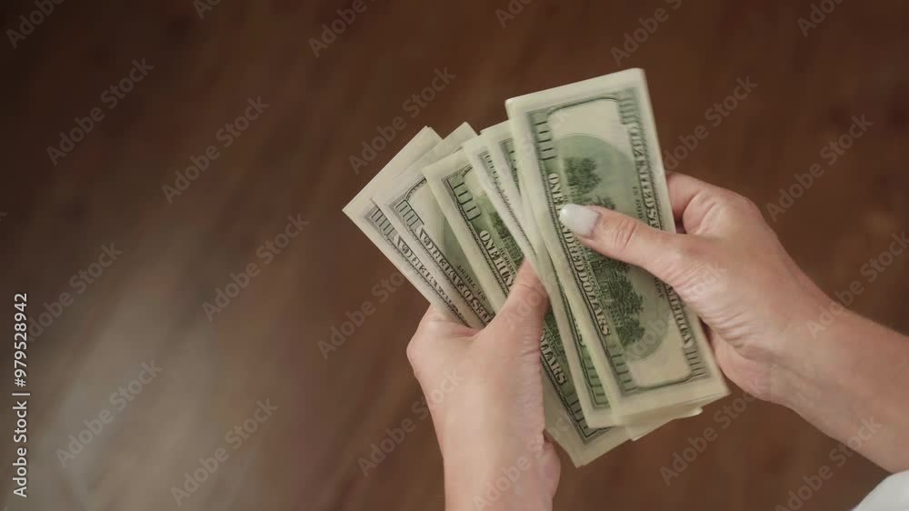 Woman counts a stack of us dollar bills, showcasing the act of handling ...