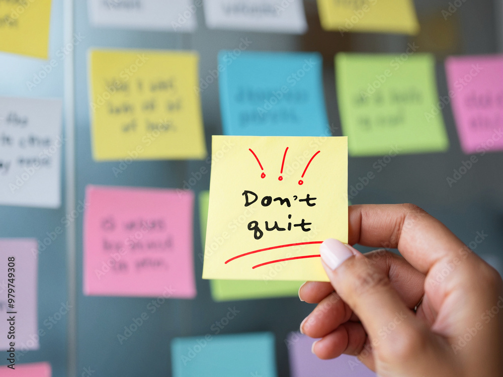 Close-up of a hand holding a sticky note with "Don't quit" written ...