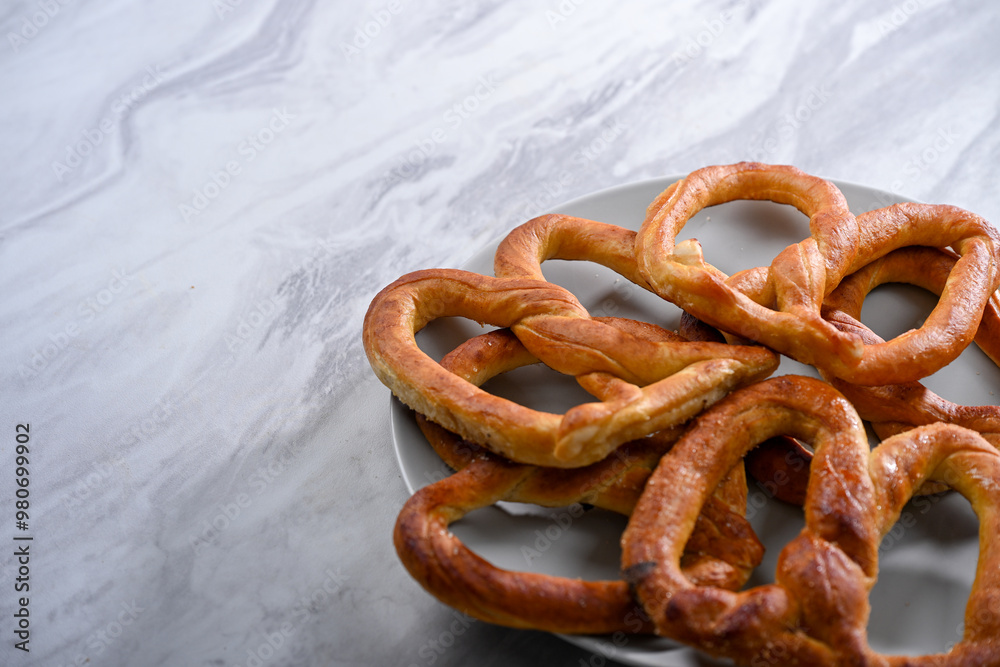 A plate of golden, freshly baked pretzels placed on a sleek white ...