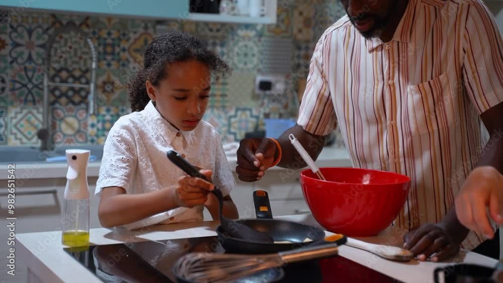 African American father man hand frying pancakes together with daughter ...