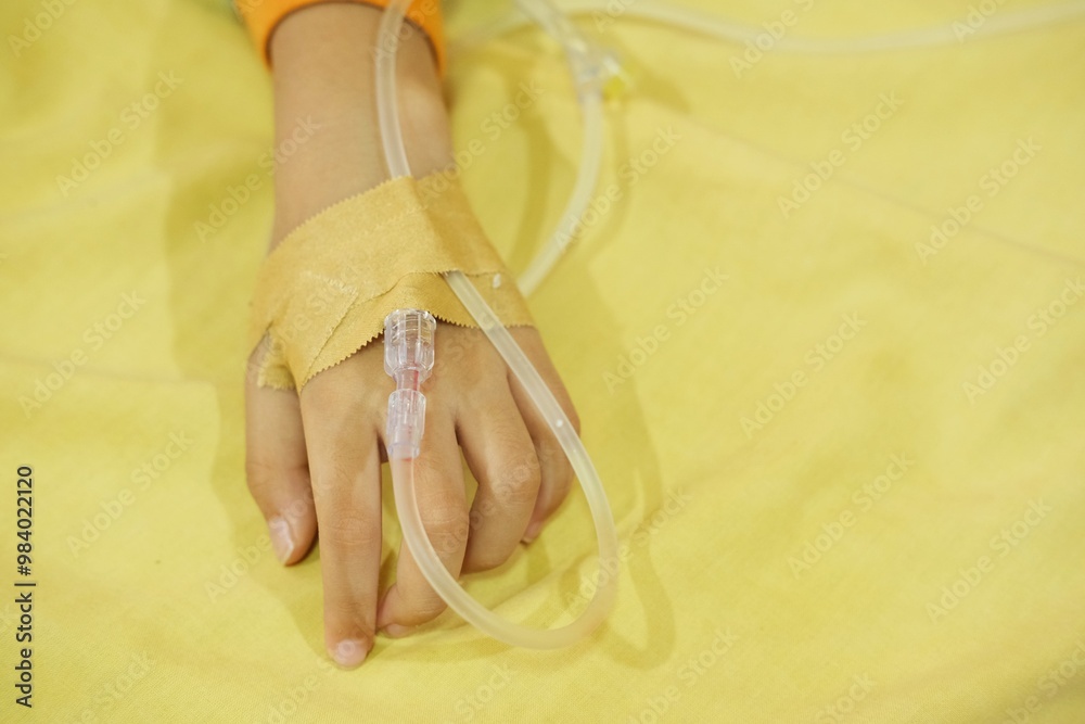 Close-up of a patient's hand with an IV catheter inserted, resting on a ...