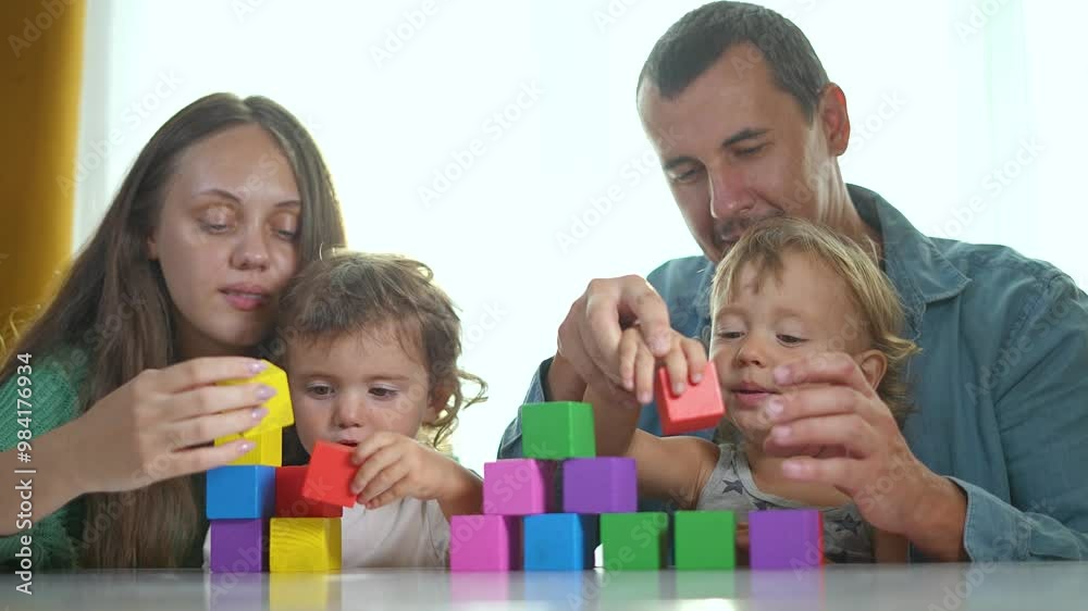 Family playing with colorful constructor cubes at home. Parents helping ...