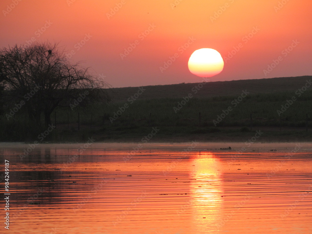 Different sunrise. Sun rising behind the hill and reflecting in the ...