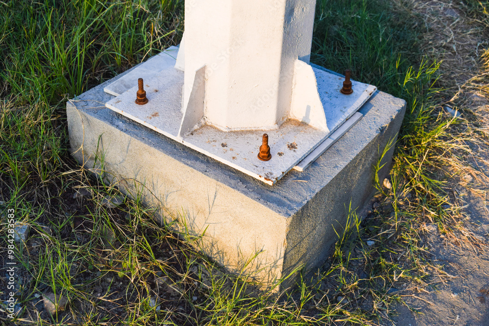 Base of a large metal pole bolted to a concrete foundation, bolt and ...