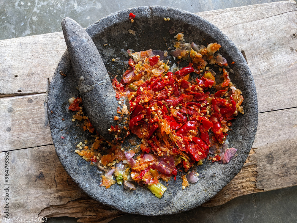 Sambal, a traditional Indonesian chili paste, being made in a stone ...