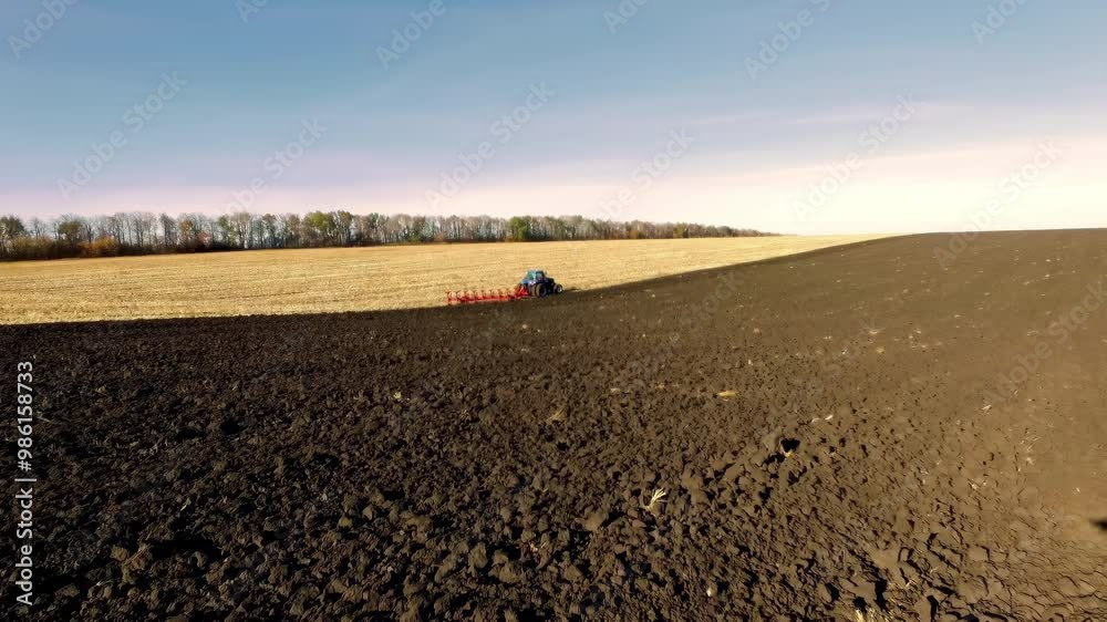 A powerful tractor with a plough ploughs a field, turning over fertile ...