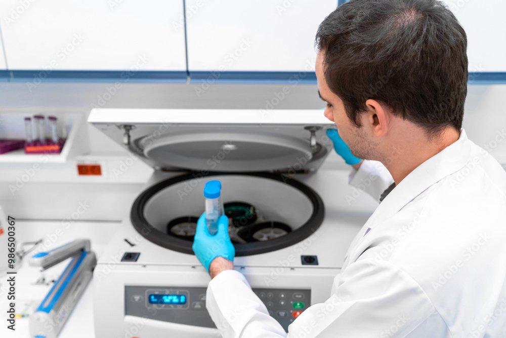 Laboratory technician using refrigerated centrifuge machine in blood ...