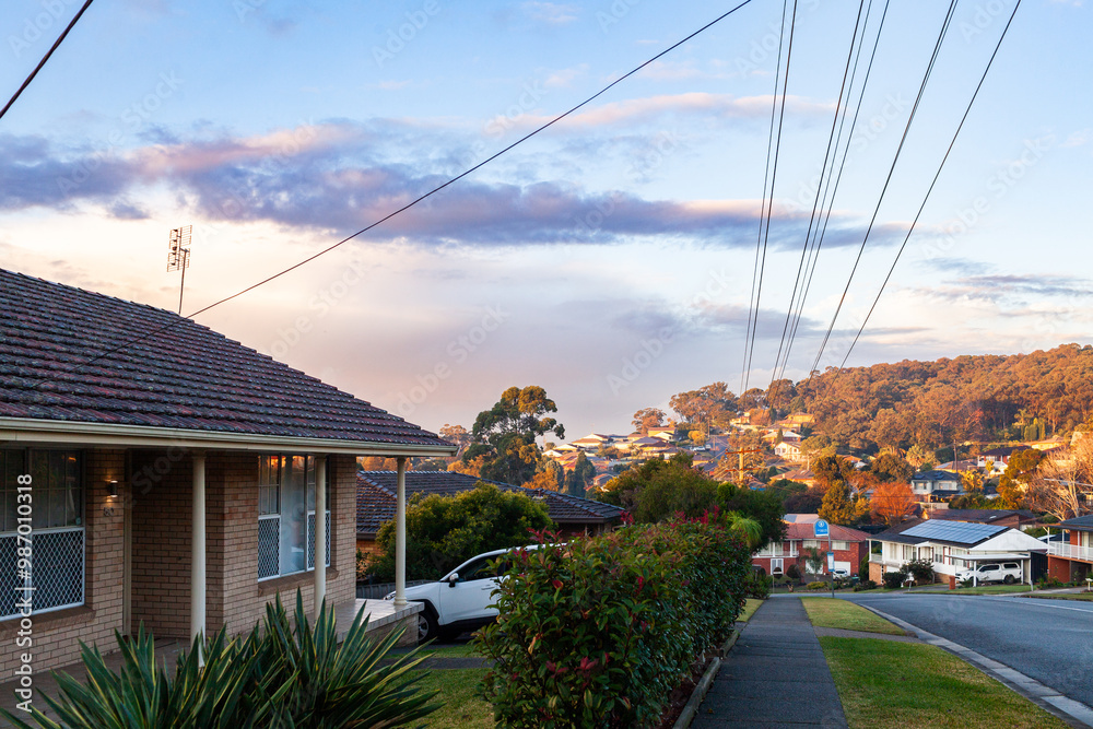 footpath and home beside street at dusk with bus stop sign and overhead ...