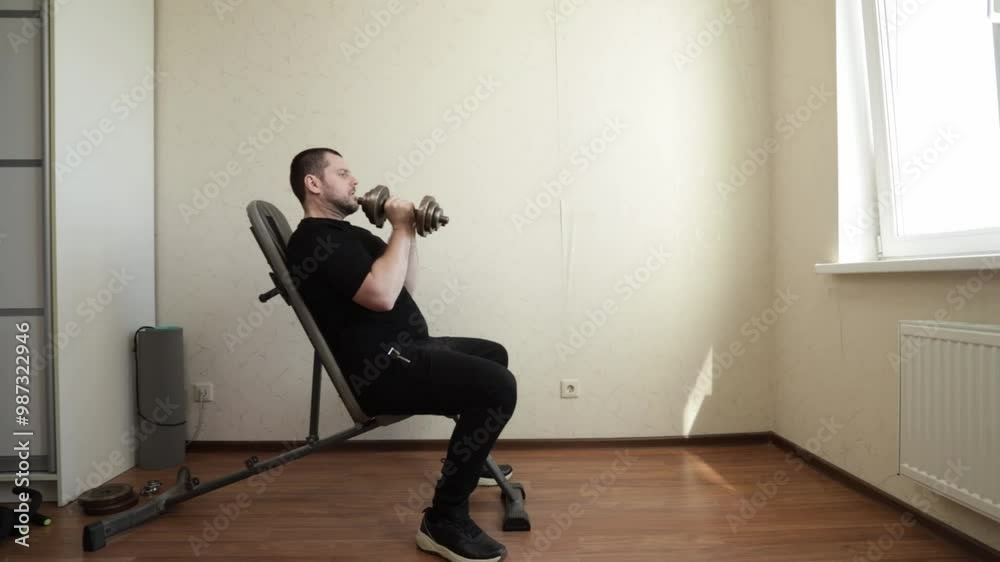 Man exercising in home gym, working out with dumbbells to build muscles ...