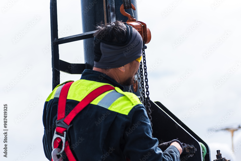 A deck crew member of a merchant ship working at height, equipped with ...