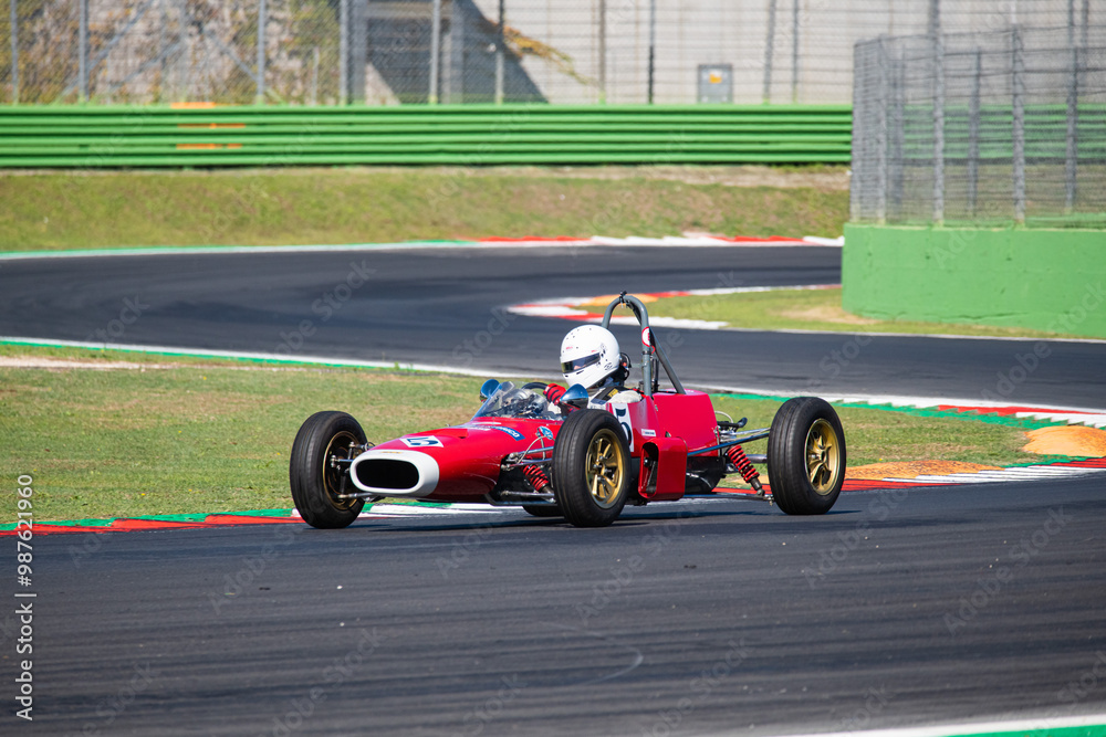 Classic vintage formula racing car speeds around a turn on a racetrack ...