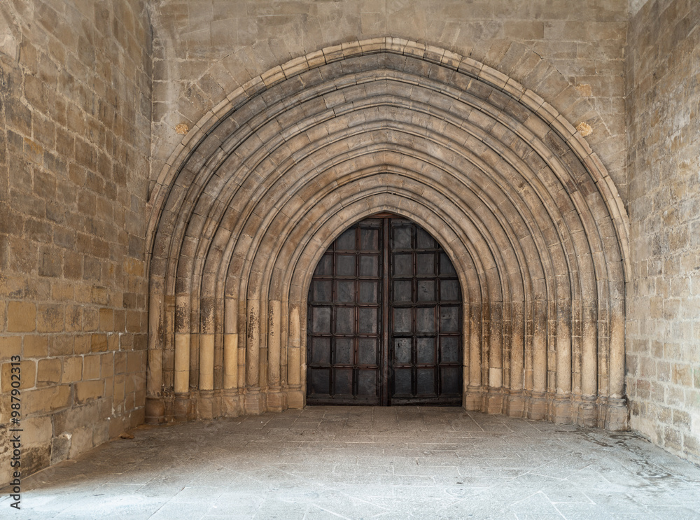 This image shows a large, dark wooden door set within a detailed stone ...
