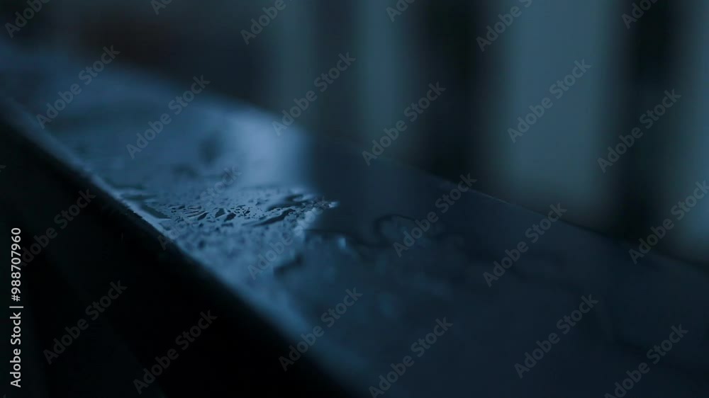The video shows a rain-soaked railing in slow motion. Water droplets ...